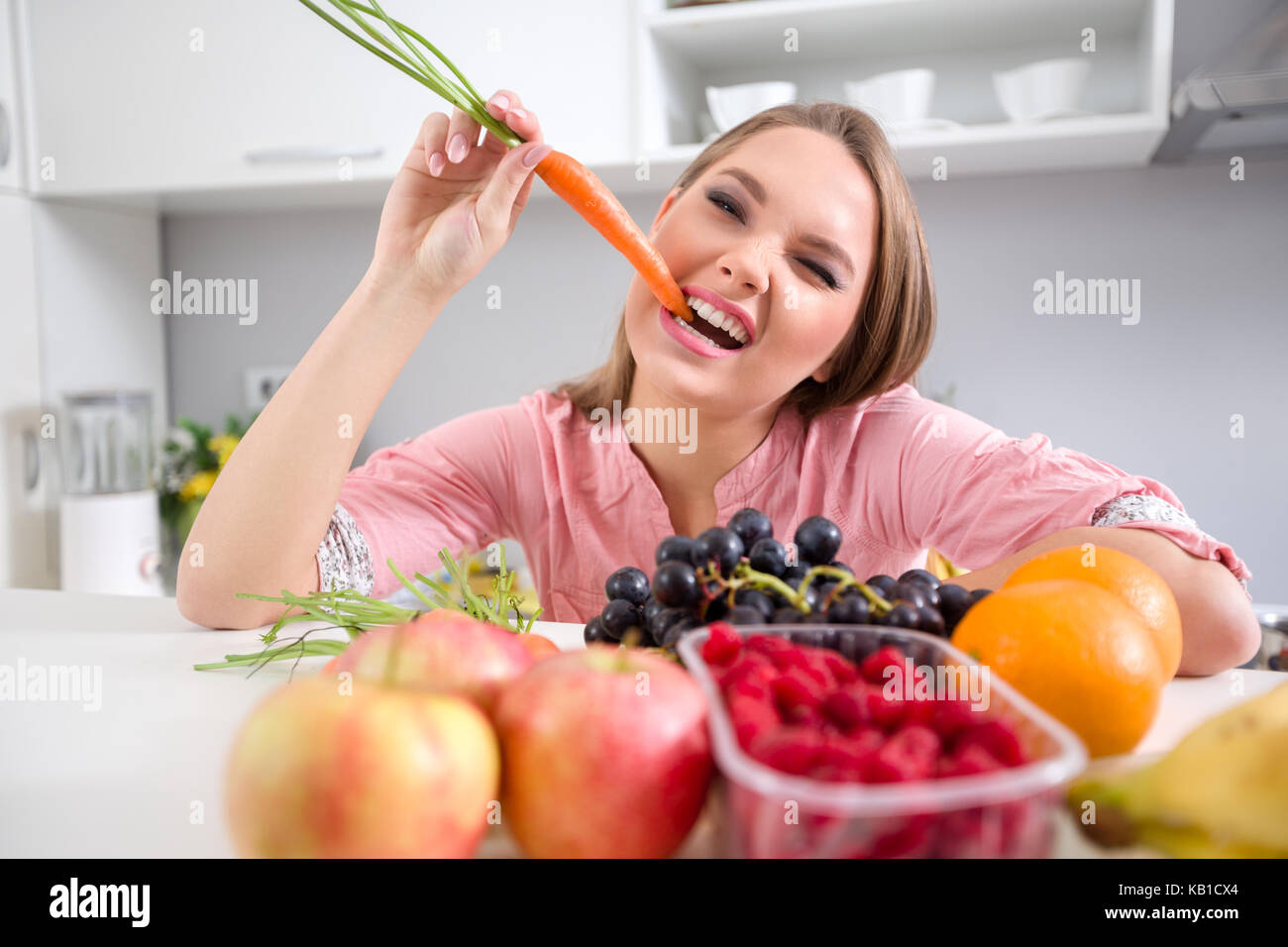 Funny girl biting a carrot, she eating healthy food Stock Photo - Alamy