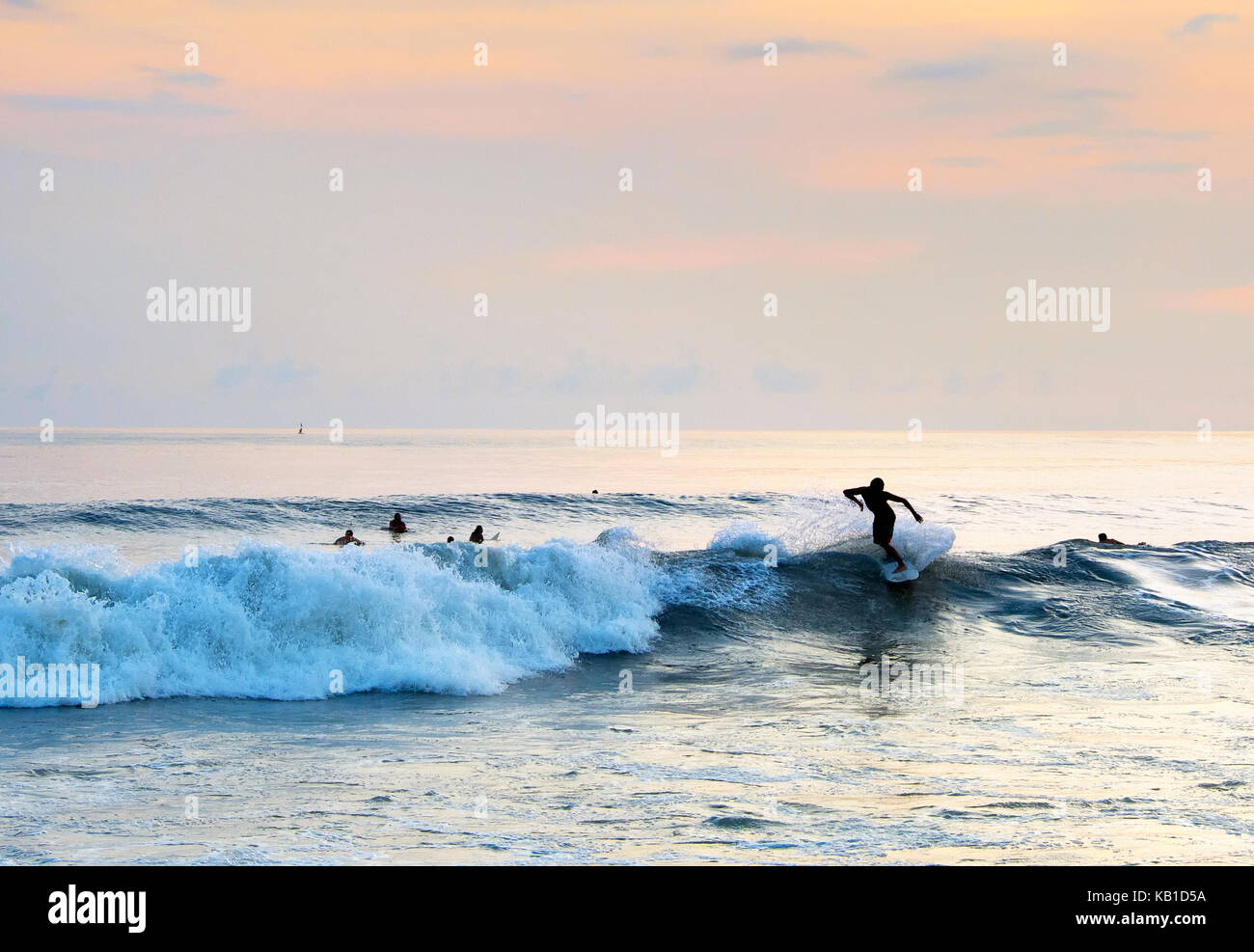 Surfer riding a wave in the ocean at sunset. Bali island Stock Photo ...