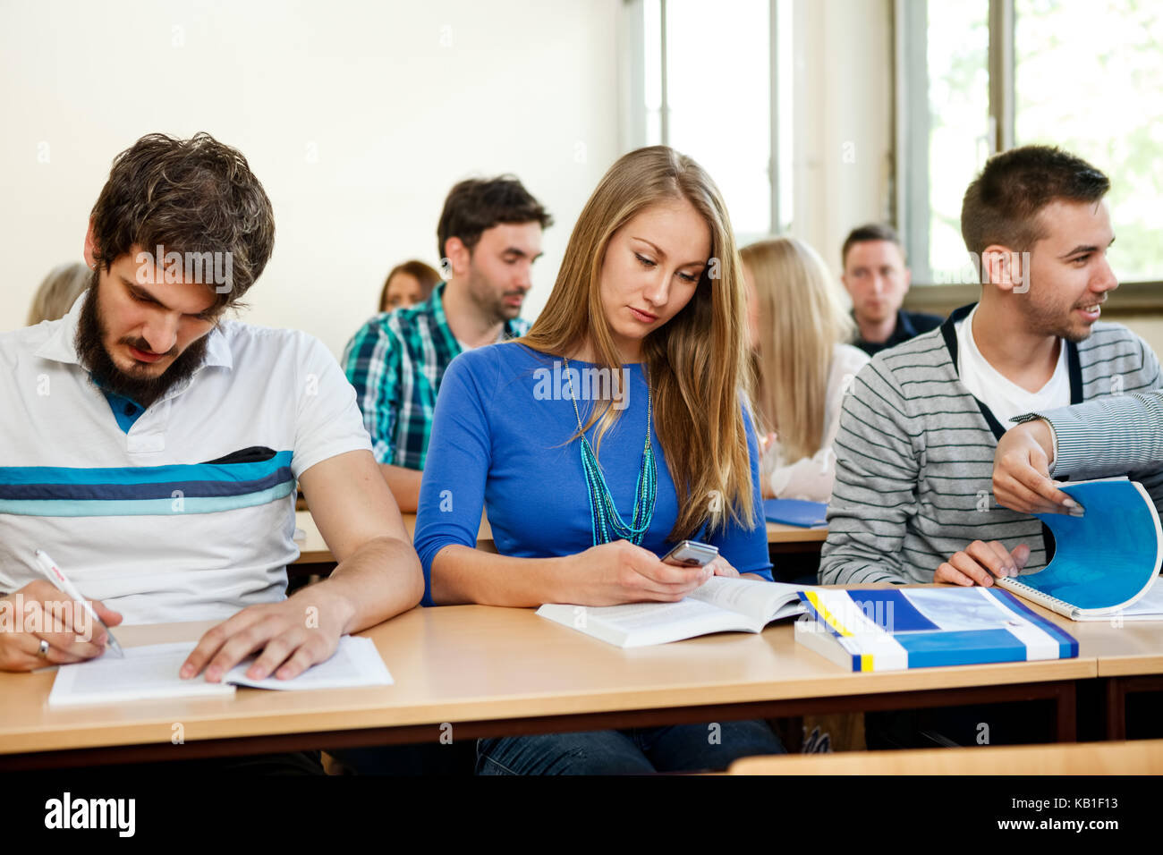 Young students taking notes in a classroom Stock Photo - Alamy