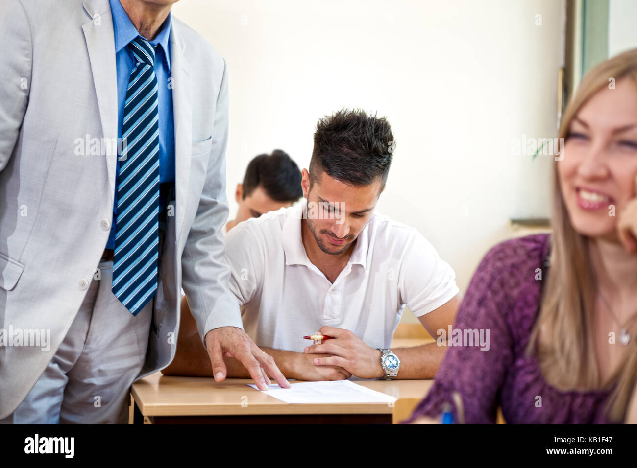 Teacher checking student work in a classroom Stock Photo - Alamy