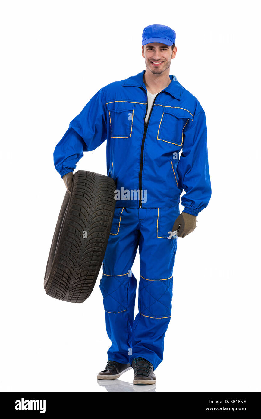 Smiling young mechanic holding tire for the car, over white Stock Photo ...