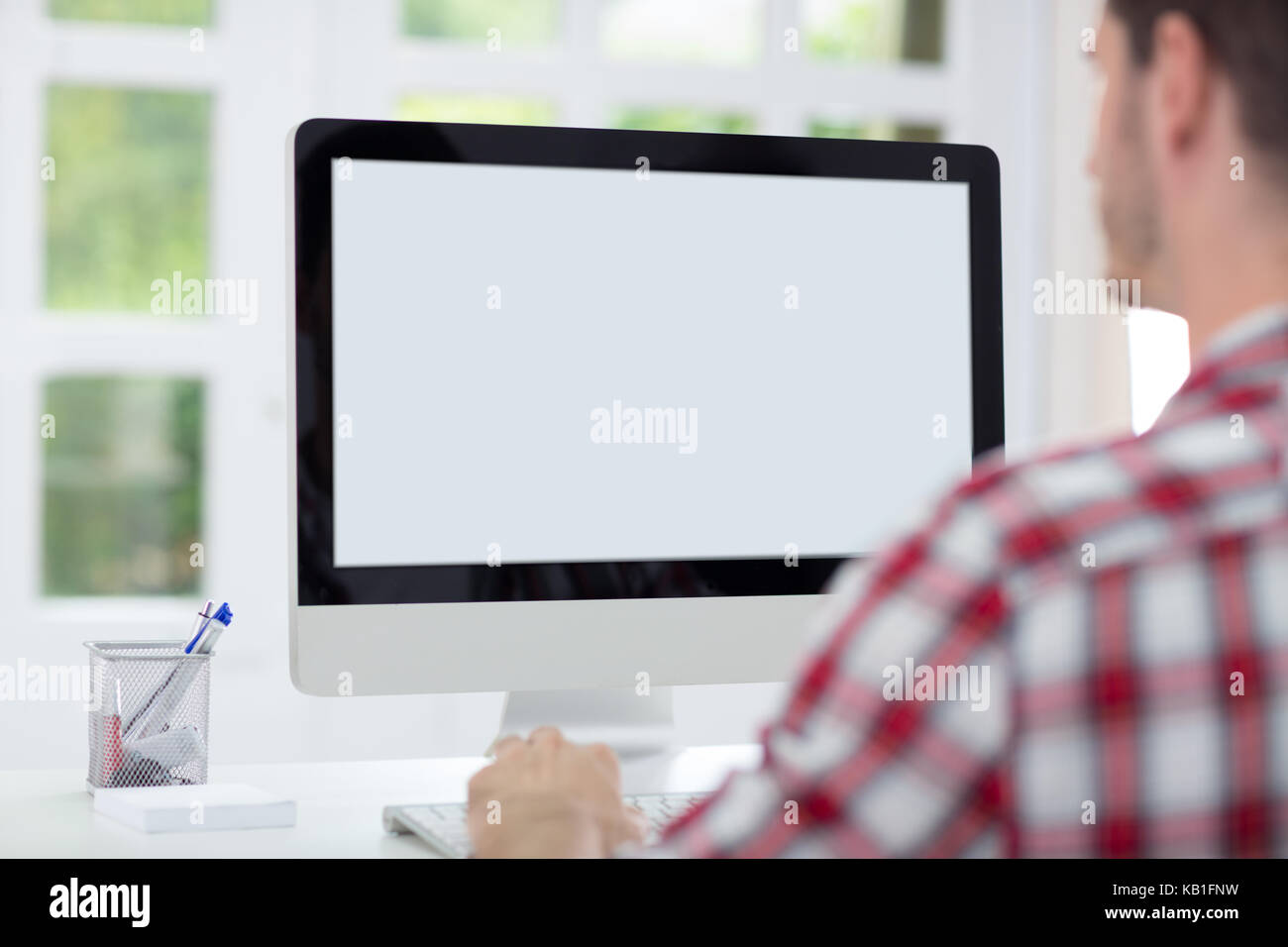 Young man working in bright office looking at computer screen Stock ...