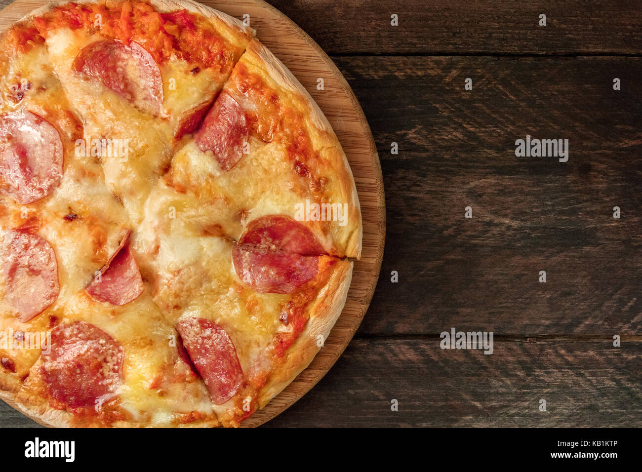 A closeup photo of a cut pepperoni pizza, shot from above on a dark ...