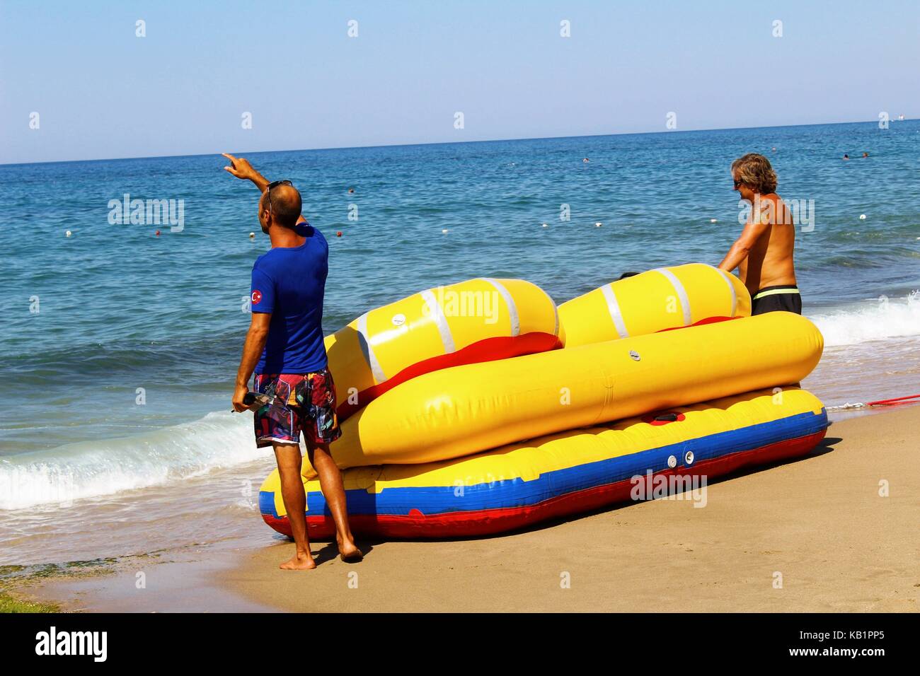 Two men are preparing to launch an inflatable raft for entertainment on ...