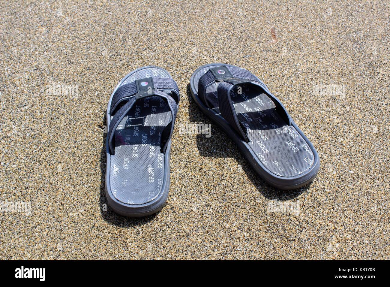 Men's beach slippers are lying on the sand Stock Photo - Alamy