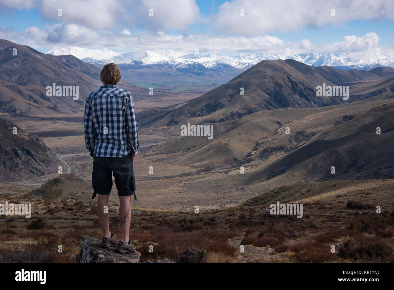 man looking over a valley with big snowy mountains Stock Photo - Alamy
