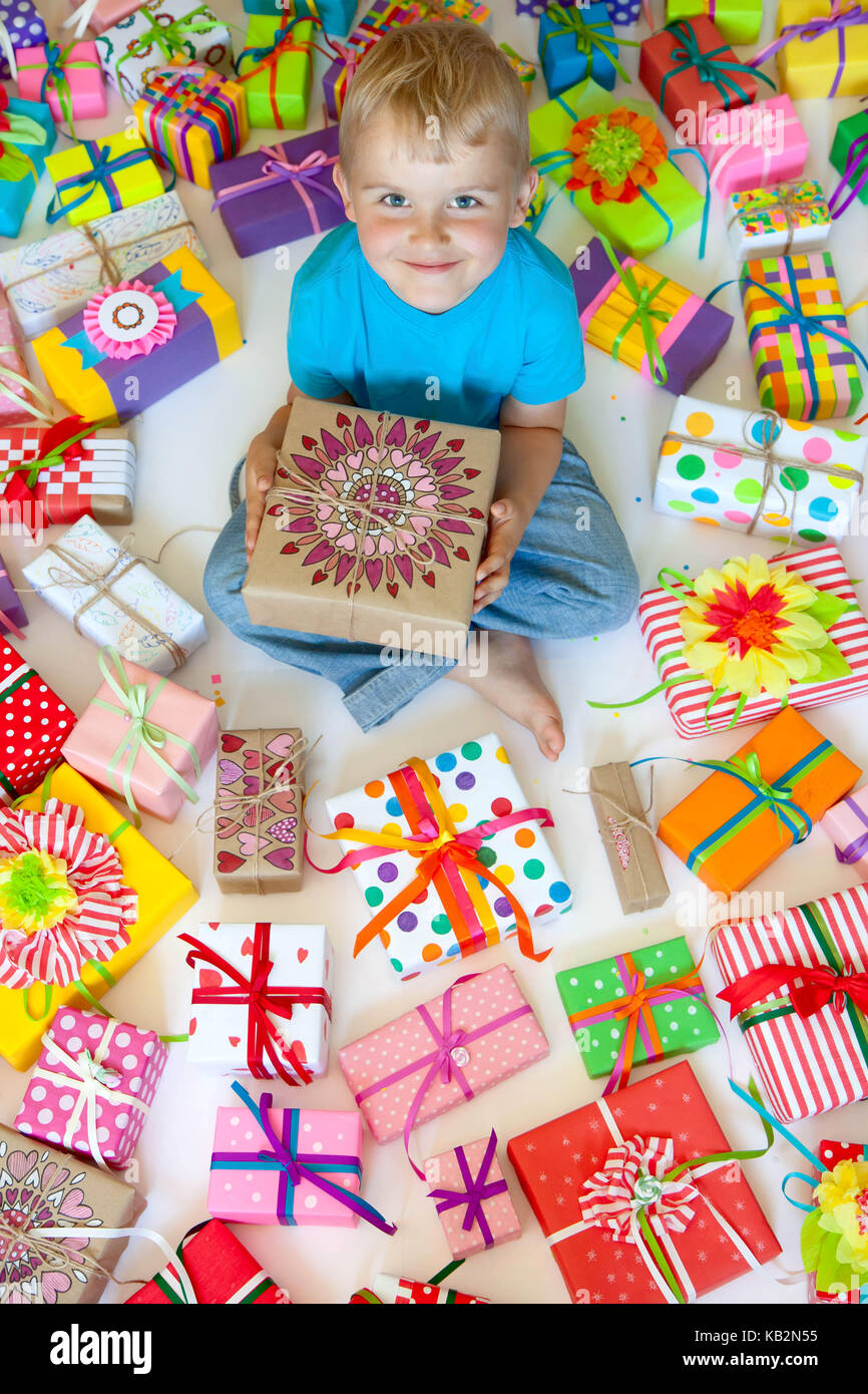 The child is holding a beautiful gift. The boy sits on the floor, and ...