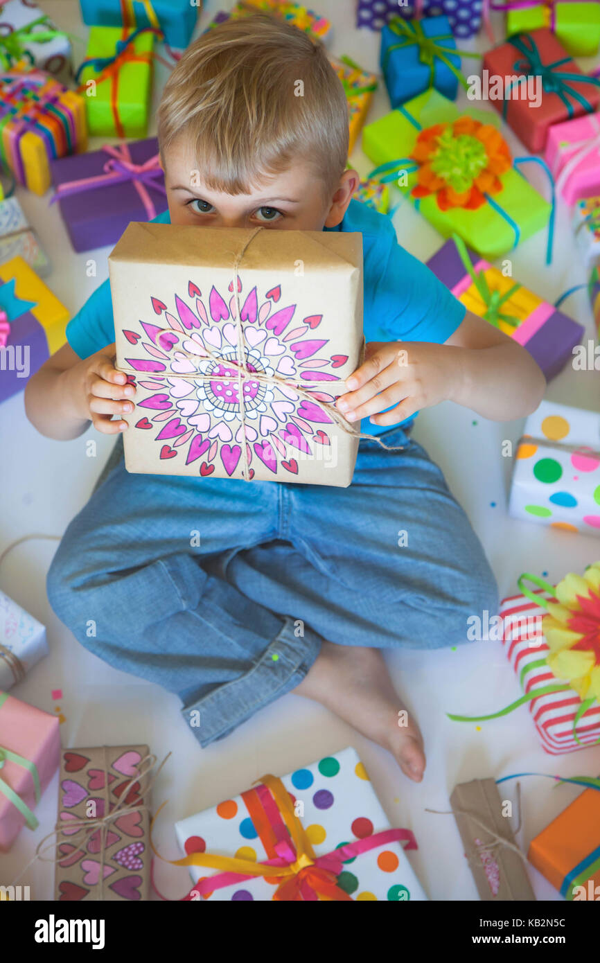 The child is holding a beautiful gift. The boy sits on the floor, and ...