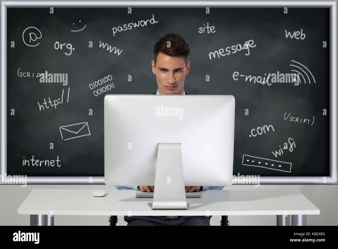 Internet man working at computer with blackboard in background Stock ...