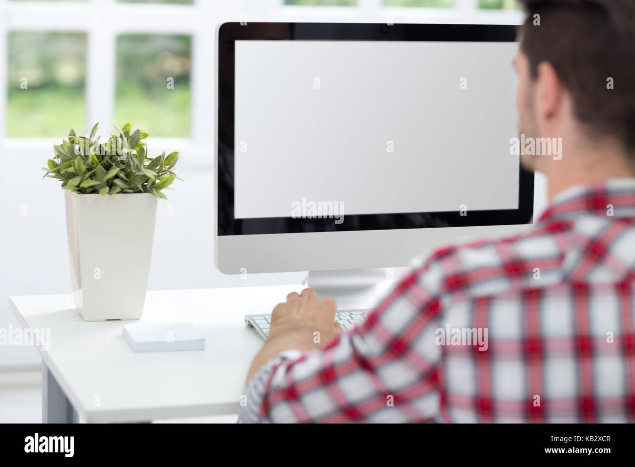 Young man looking at computer screen, working in bright office Stock ...