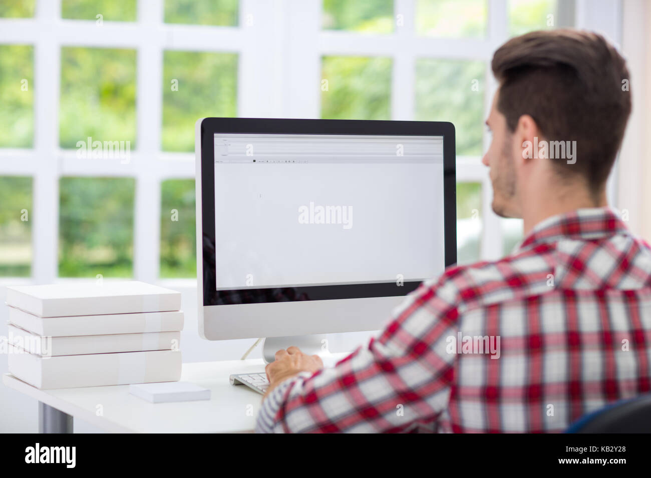 Young man looking at computer screen Stock Photo - Alamy