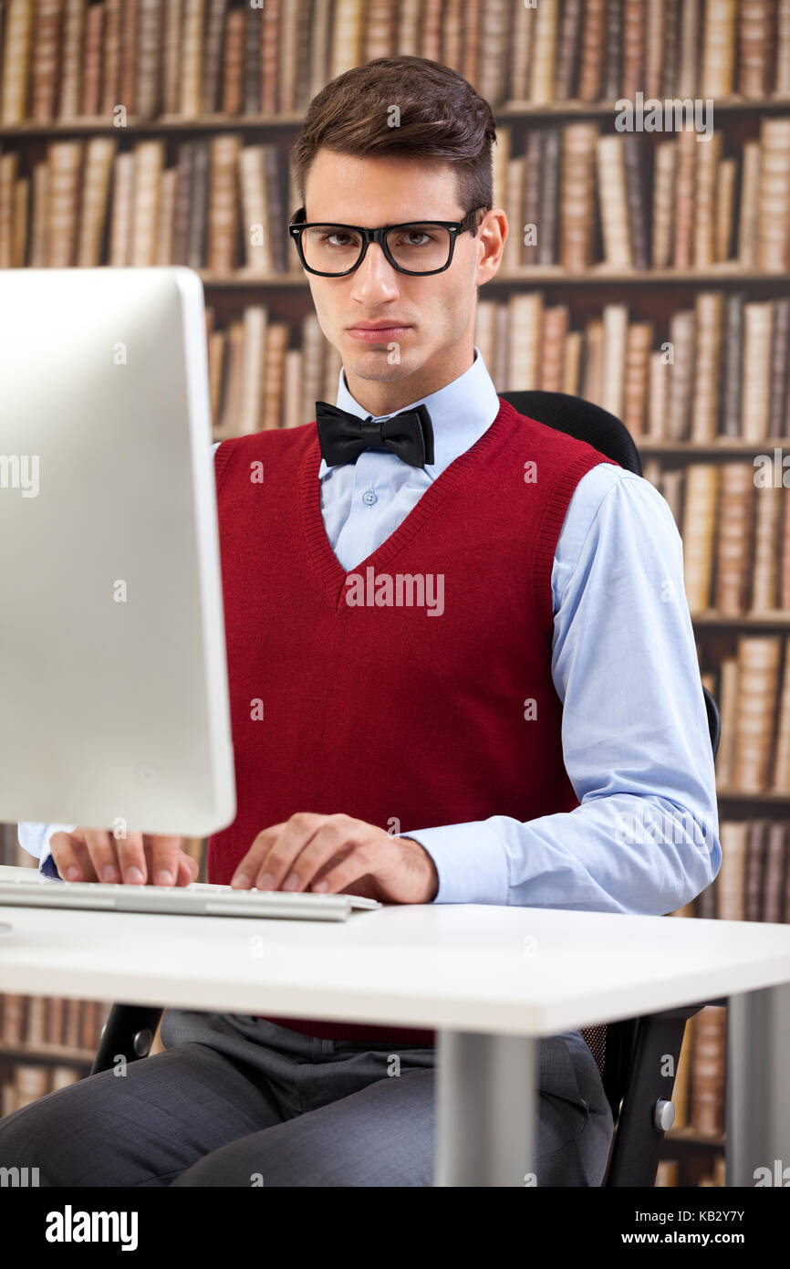Smart male student using computer in library Stock Photo - Alamy