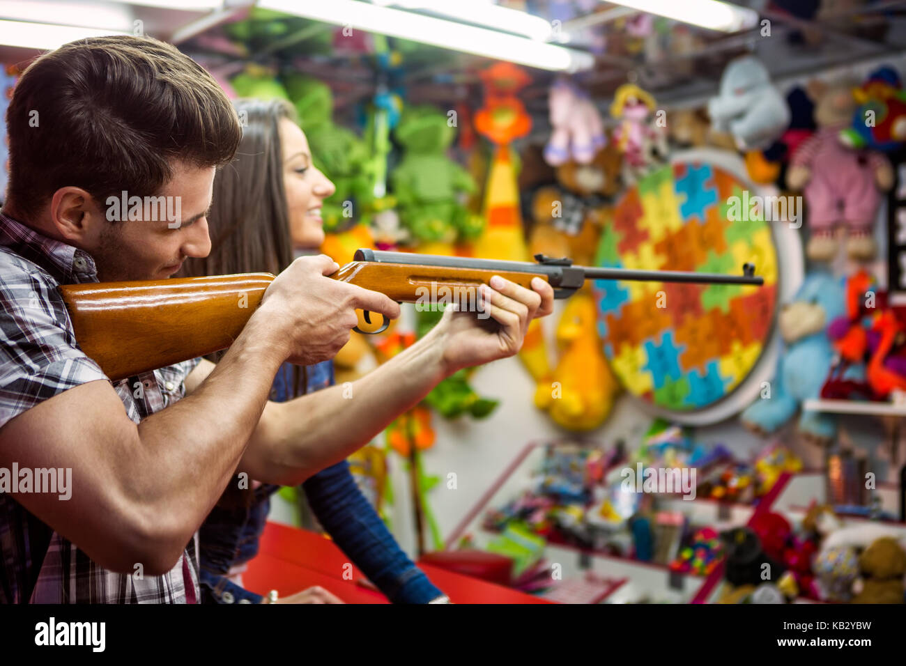couple playing shooting games while visiting an amusement park, young ...