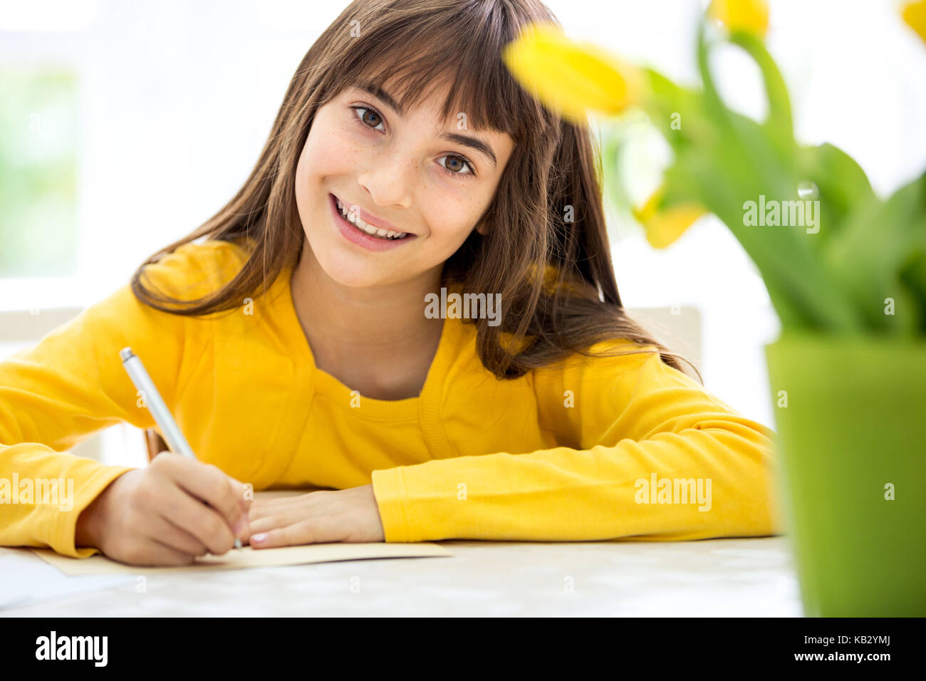 Cute little girl writing her homework at the table Stock Photo - Alamy