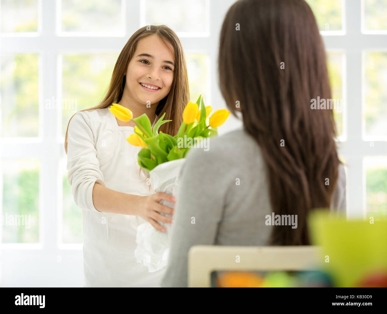 Girl giving bunch of beautiful, yellow tulips her mother Stock Photo ...