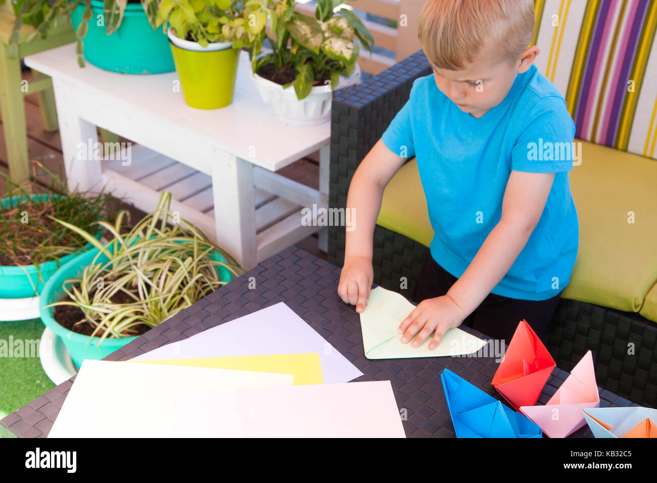 The boy makes a boat out of paper. The child is learning and doing ...