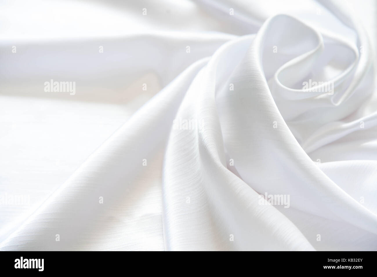 White shiny silk folded with soft folds. Matte and glossy white fabric ...