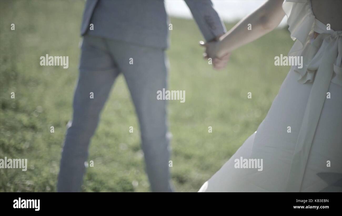 Wedding day. The groom holds the bride's hand, they walk through the ...