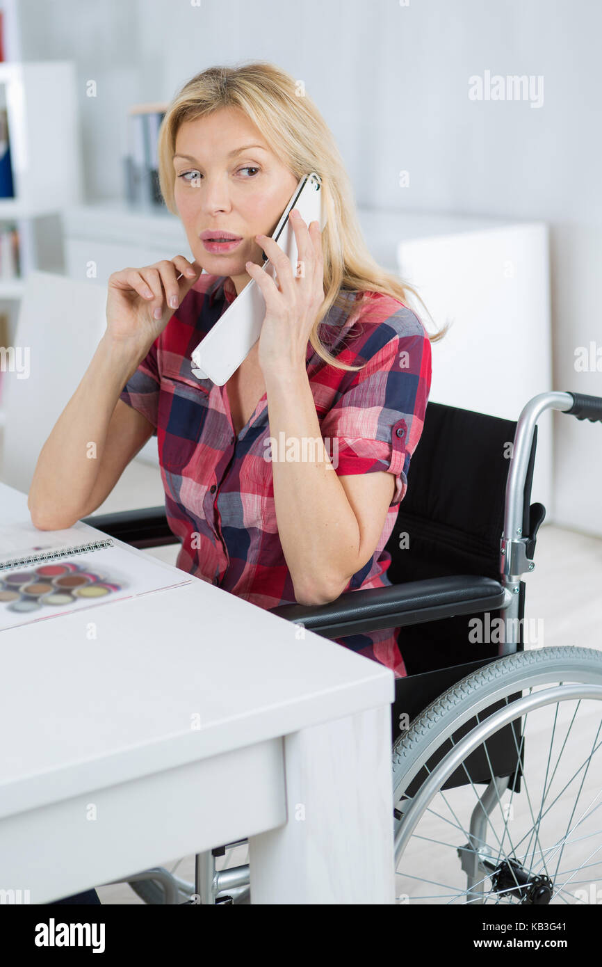 Disabled lady sat at desk on telephone Stock Photo - Alamy