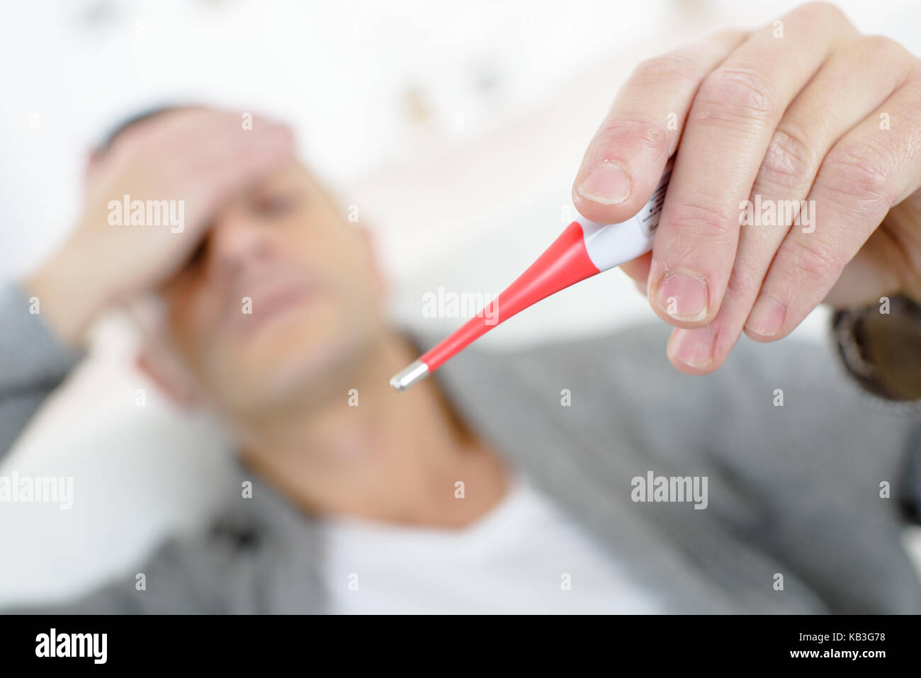man with a temperature looks at the thermometer Stock Photo - Alamy