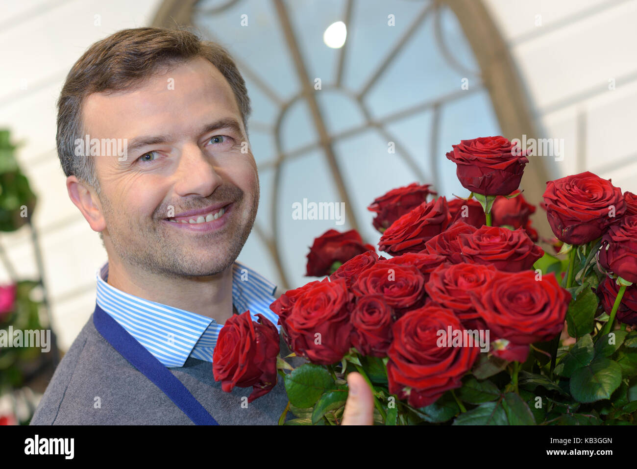 male florist holding a pot of red roses Stock Photo - Alamy