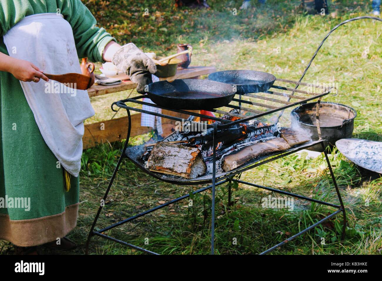 Woman in traditional clothes prepares food in a frying pan at the ...