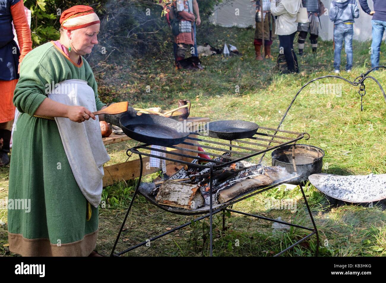 Woman in traditional clothes prepares food in a frying pan at the ...