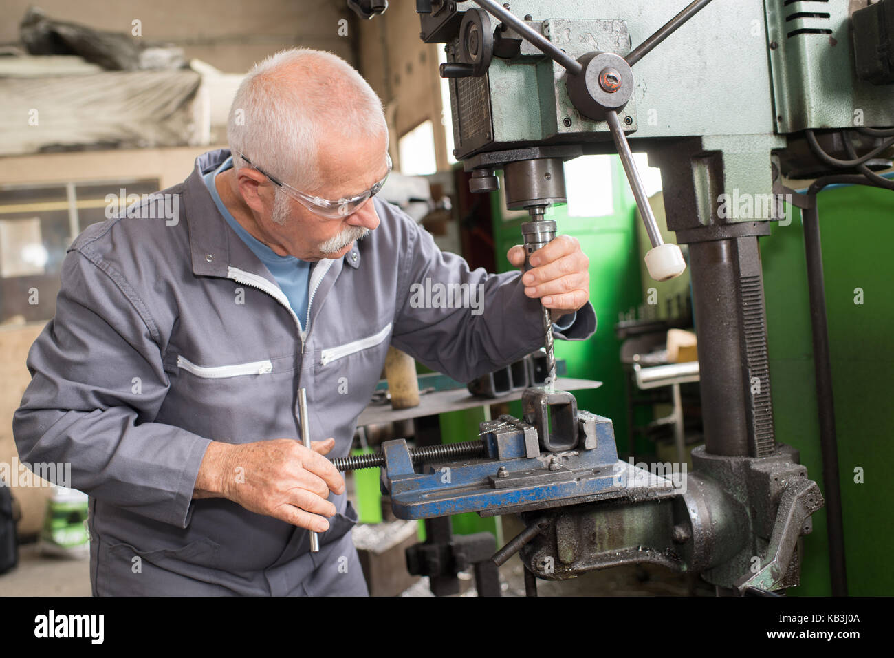 elderly worker watches processing of detail on milling machine Stock ...