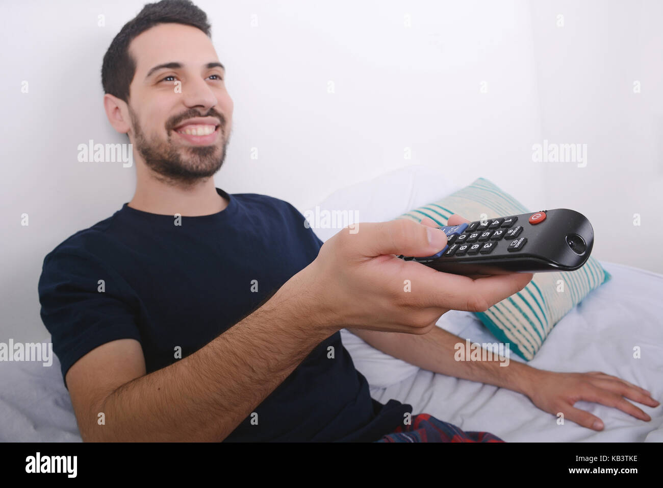 Portrait of young man watching tv and relaxed on bed. Indoors Stock ...