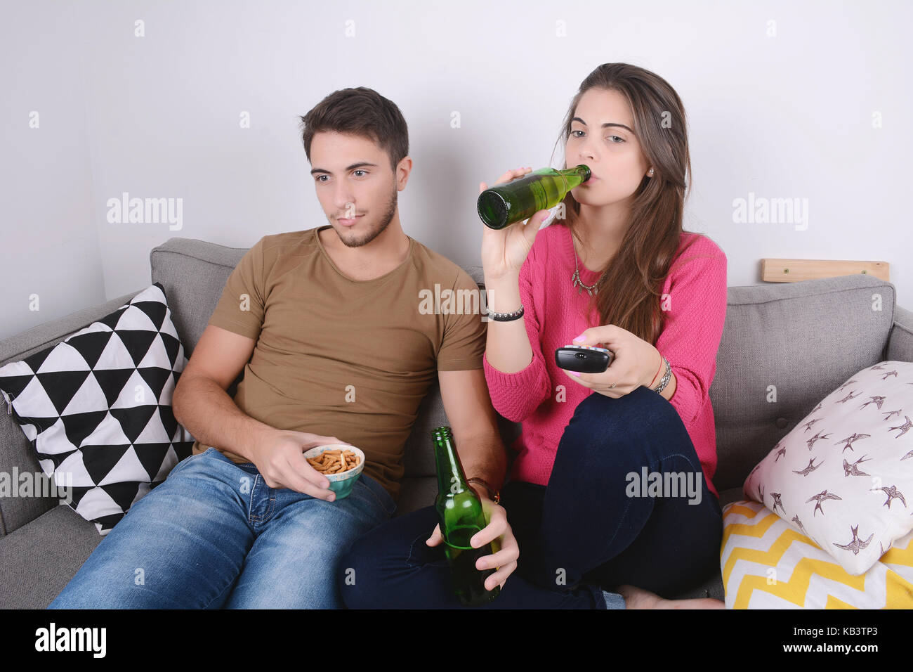 Beautiful Young Couple Drinking Beer And Watching Tv Indoors Stock