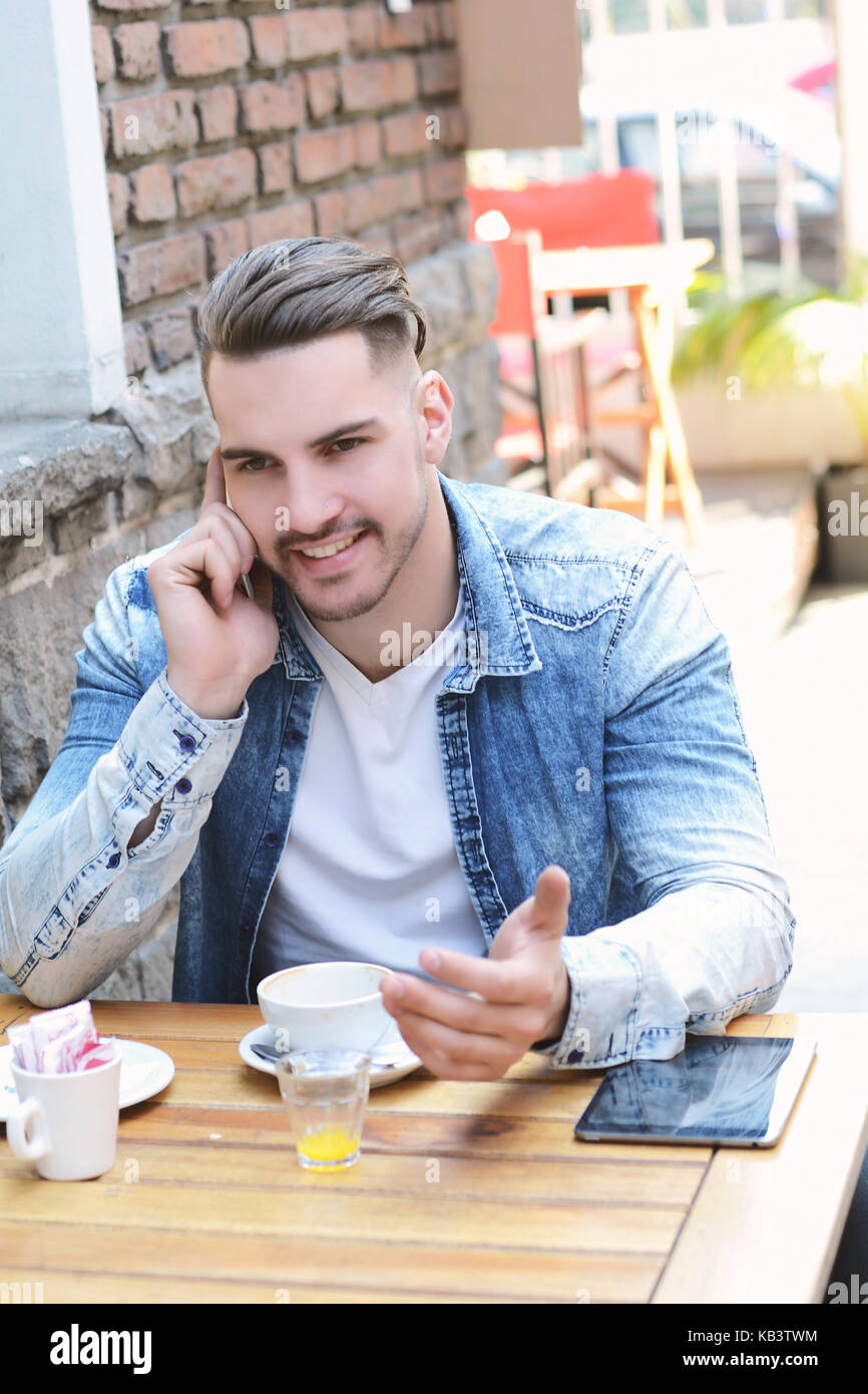Young man in coffee shop talking on the phone. Outdoors Stock Photo - Alamy