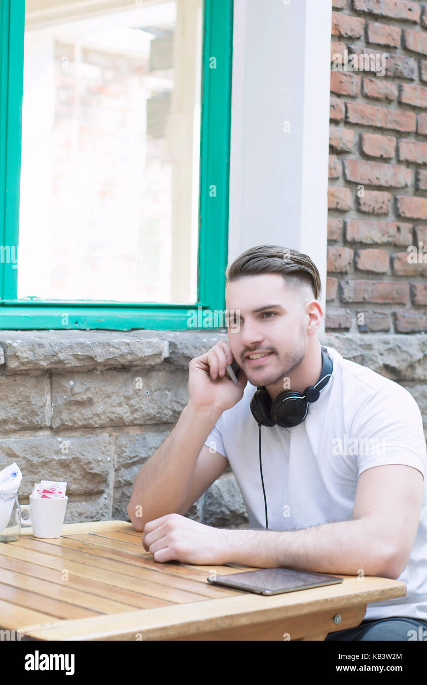 Young man in coffee shop talking on the phone. Outdoors Stock Photo - Alamy