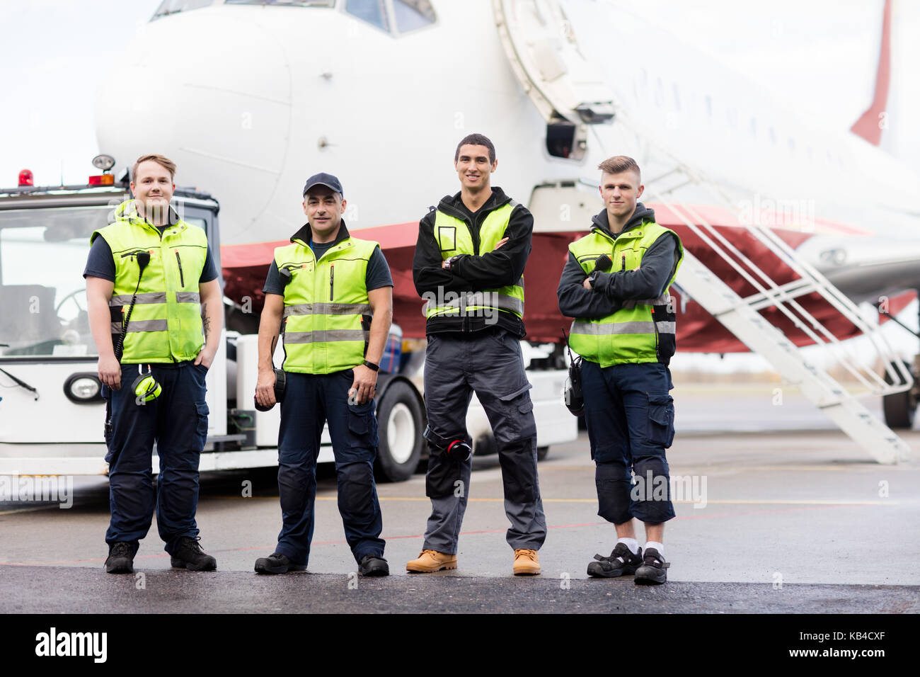 Full length portrait of ground team members with arms crossed standing ...