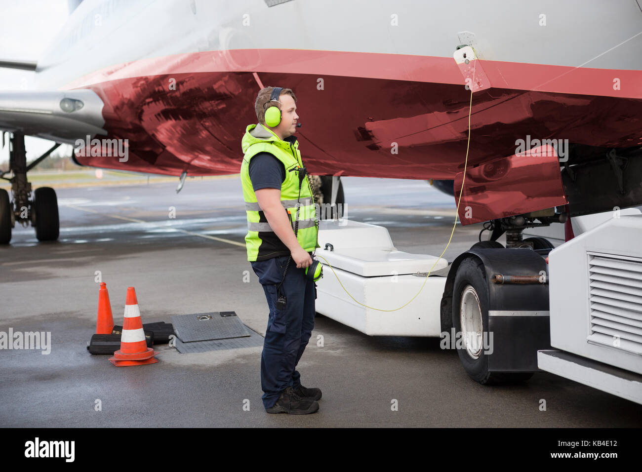 Full length side view of ground worker standing by airplane with ...