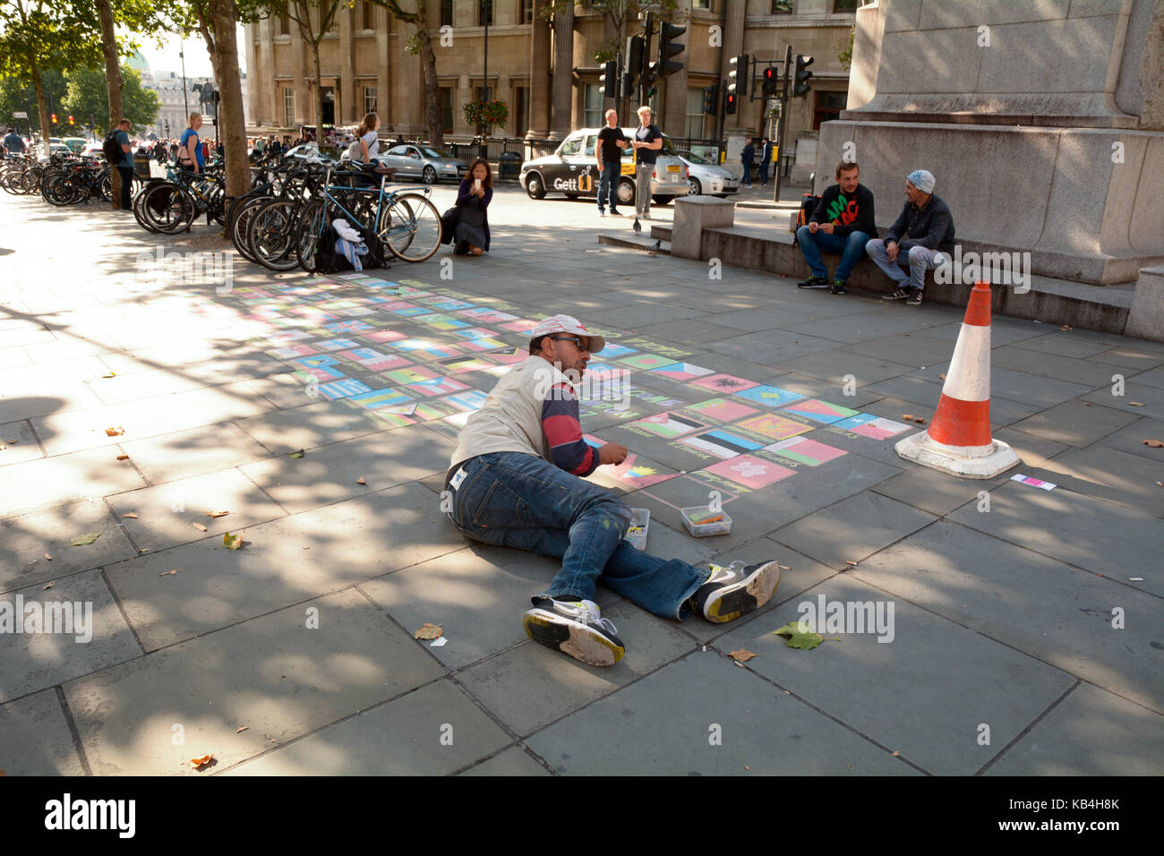Street artist producing a chalk drawing piece of art on the pavement ...