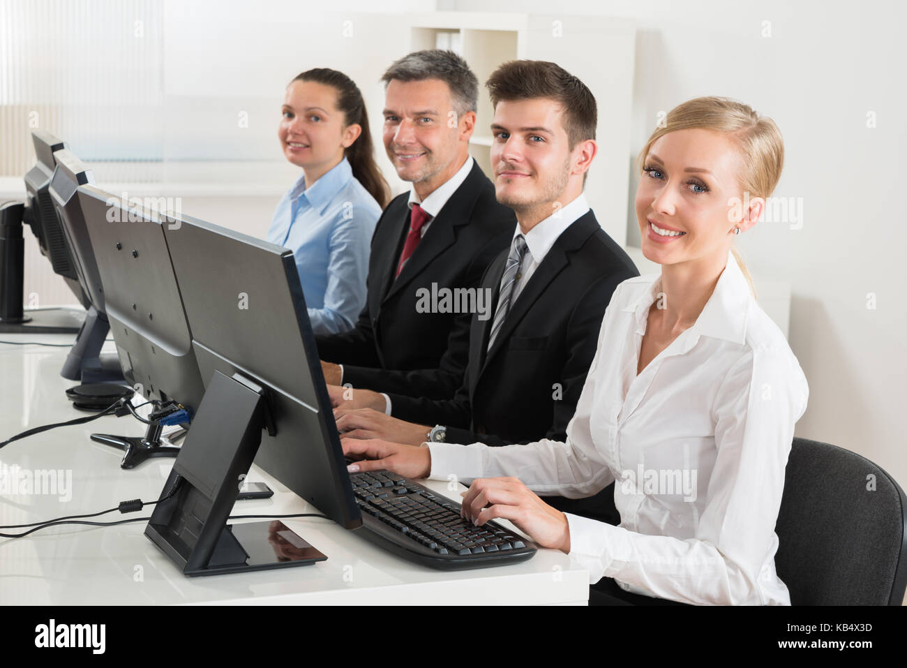 Group Of Businesspeople Typing On Desktop Computer At Desk Stock Photo ...