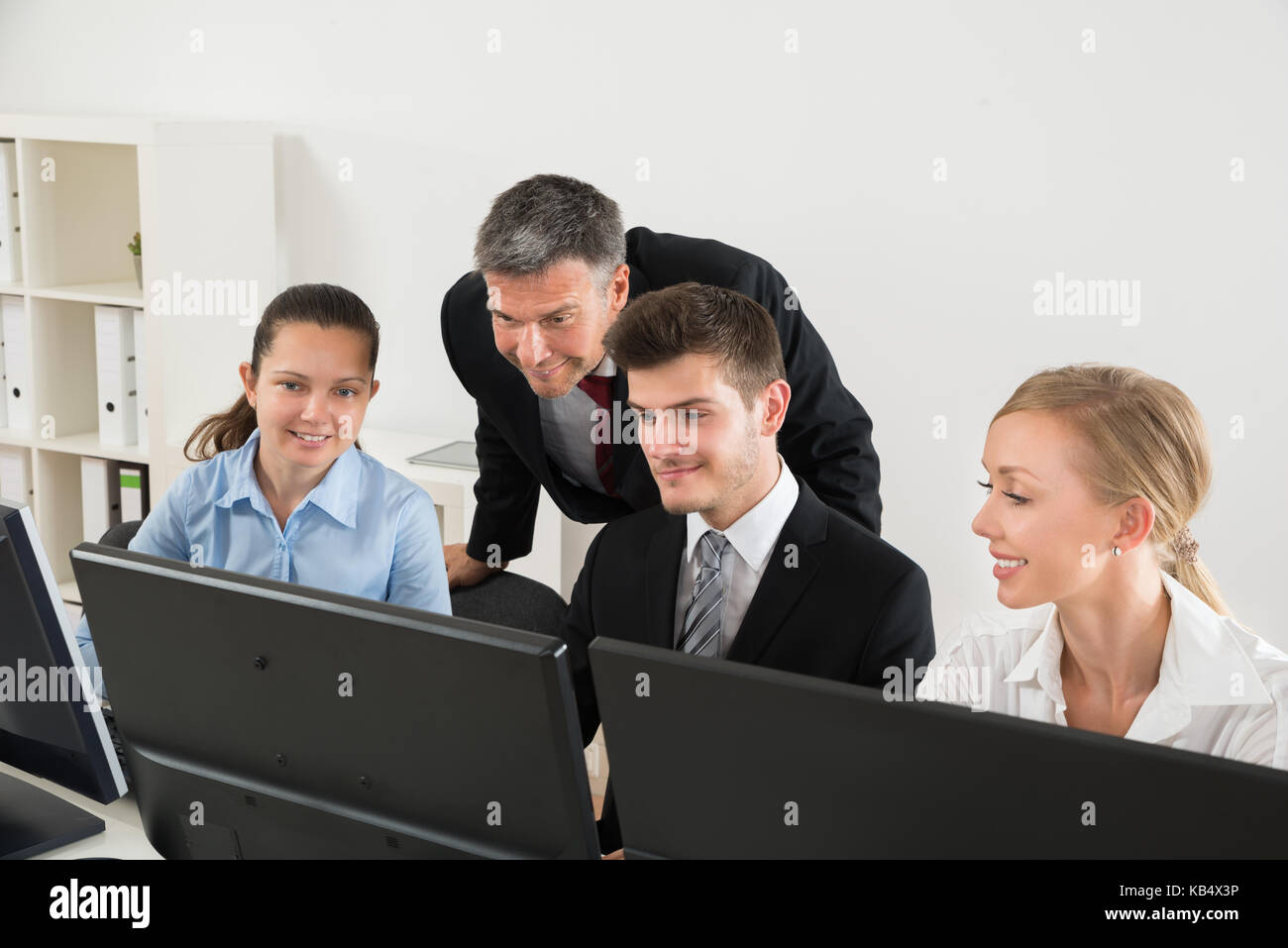 Group Of Happy Businesspeople Working On Computers In Office Stock ...
