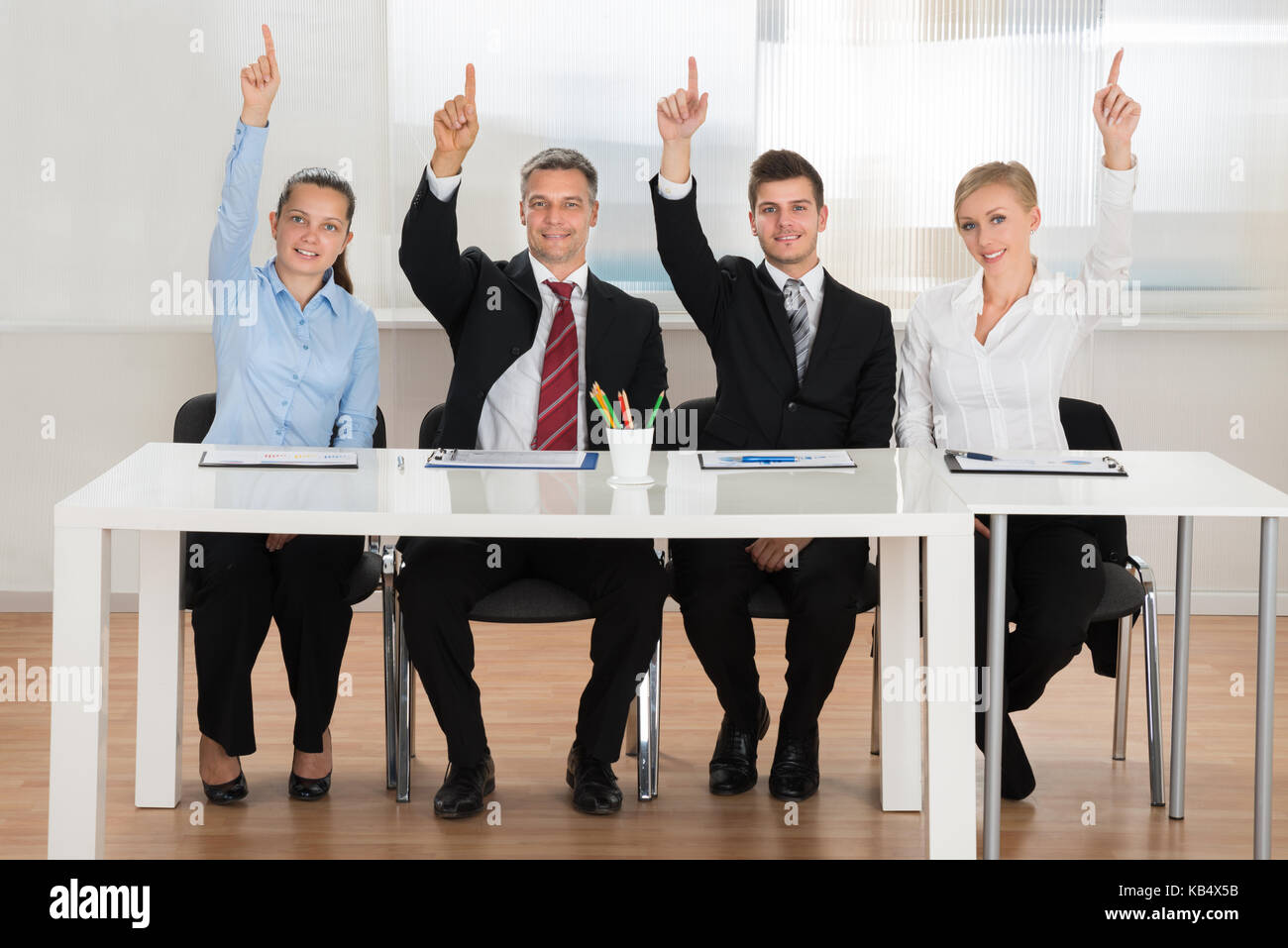 Businesspeople Team Raising Hands At Desk In Conference Stock Photo - Alamy