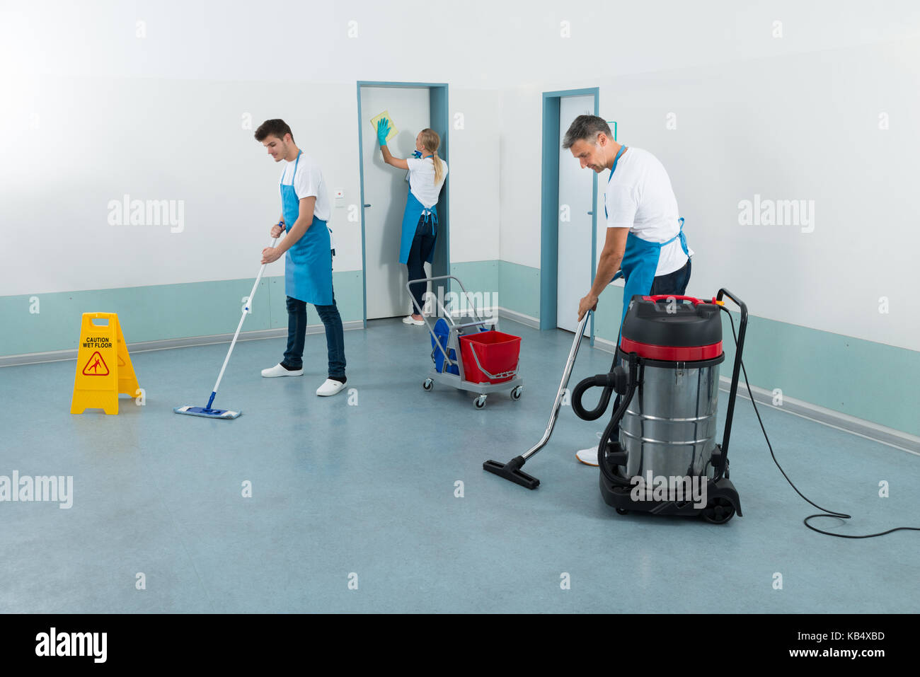 Group Of Janitors Cleaning Corridor With Cleaning Equipments Stock ...