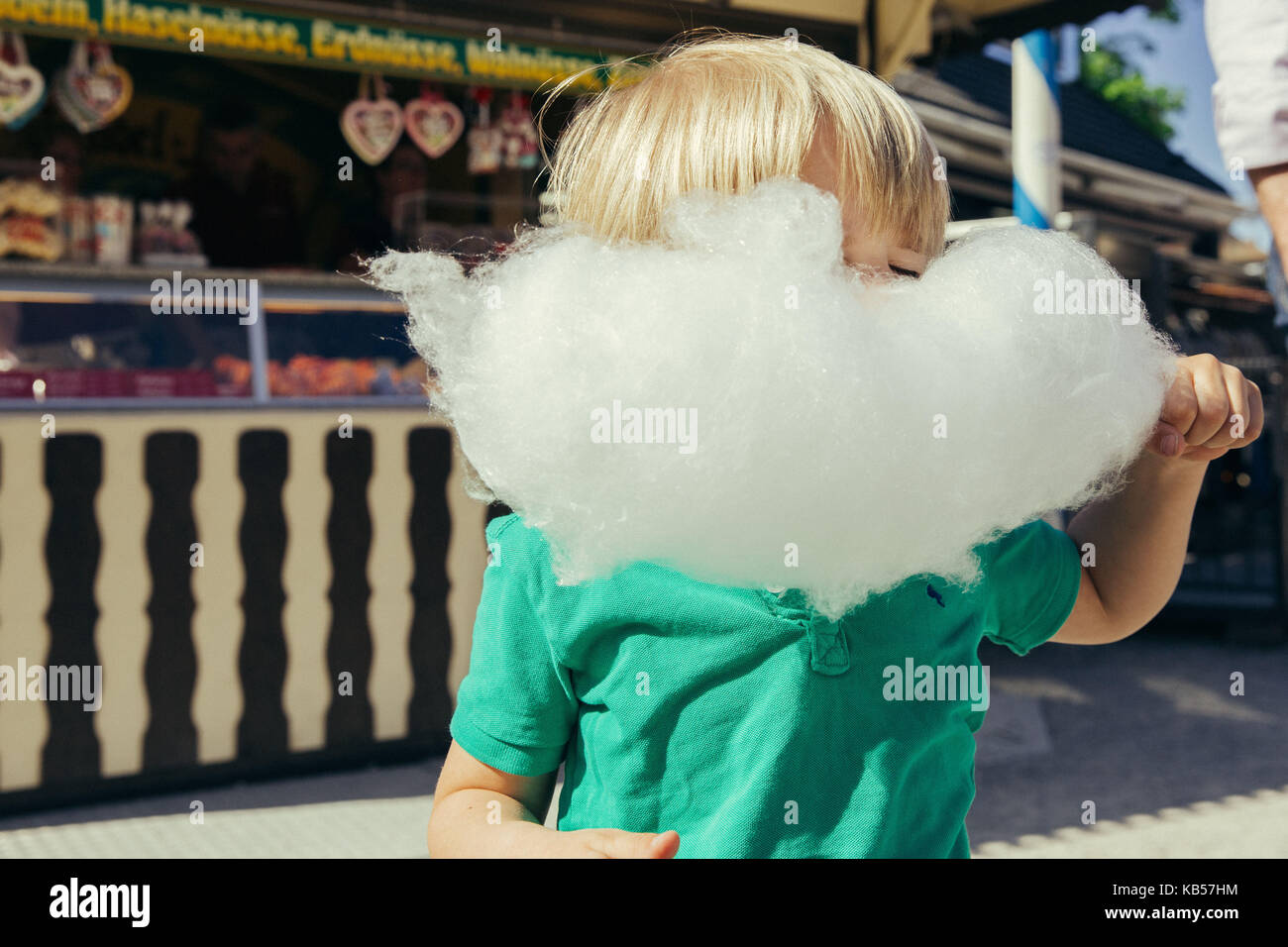 Child eats candy floss in front of fair stall hi-res stock photography ...