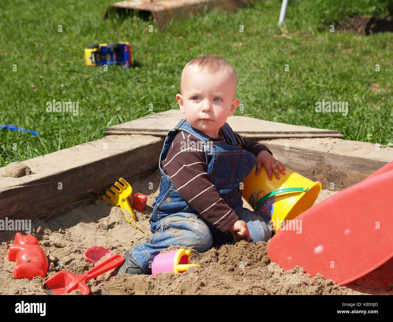 Little girl sitting inside the sand-pit Stock Photo - Alamy