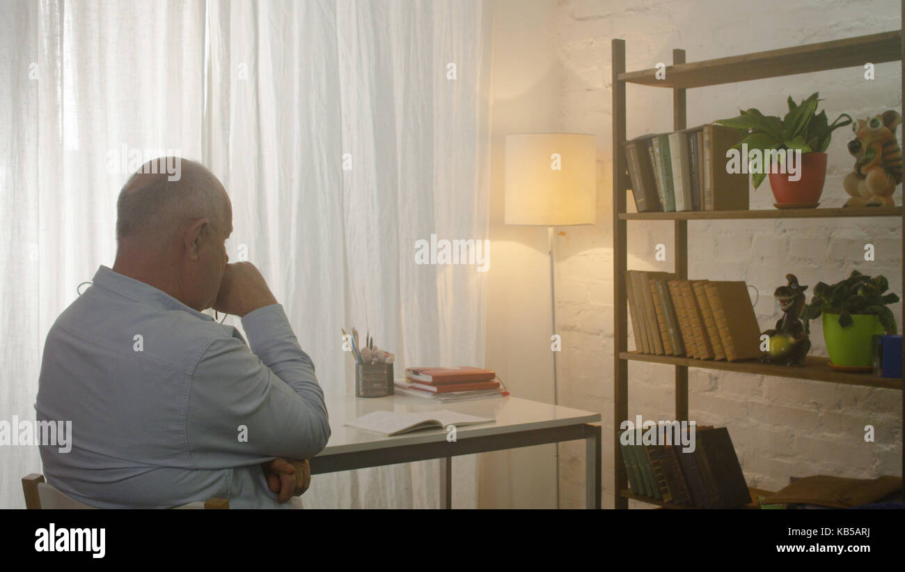 Thoughtful senior man in the living room. Sad old man sitting at the ...