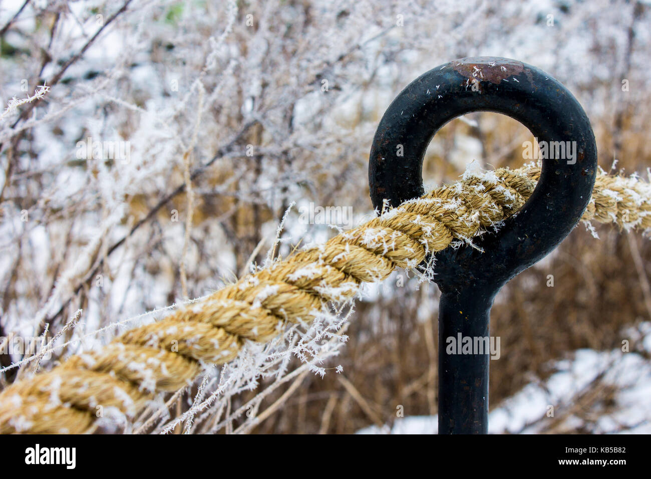Thick rope covered in snow passing through an iron round hook Stock ...
