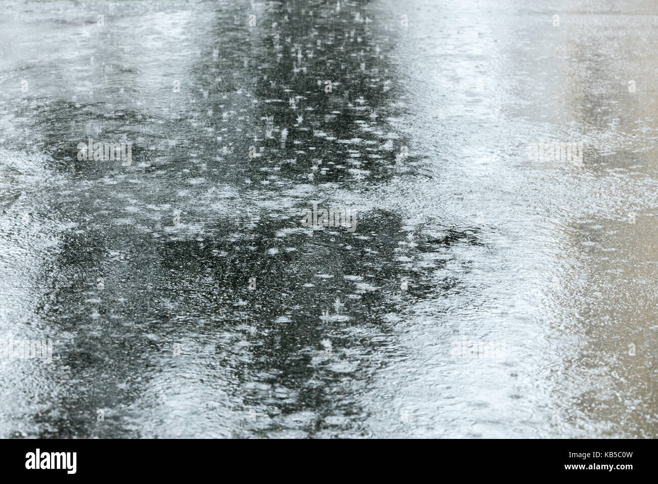 flooded city sidewalk. raindrops falling in puddles creating ripples ...