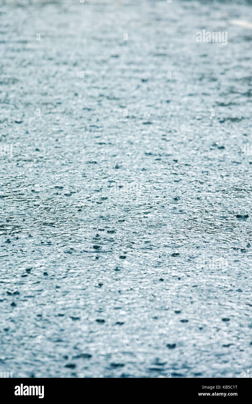 sidewalk flooded with rain water. raindrops creating ripples on water ...