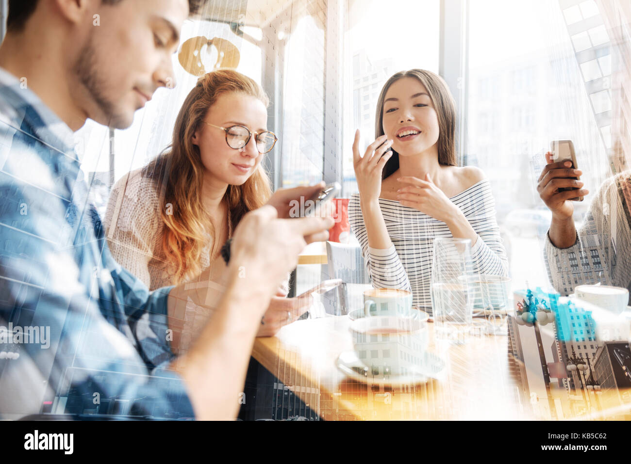 Joyful friends using mobile phones Stock Photo - Alamy