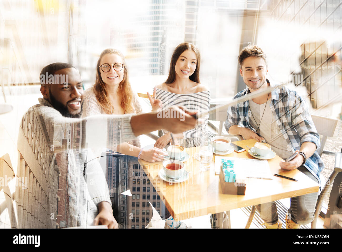 Positive friends using selfie stick Stock Photo - Alamy