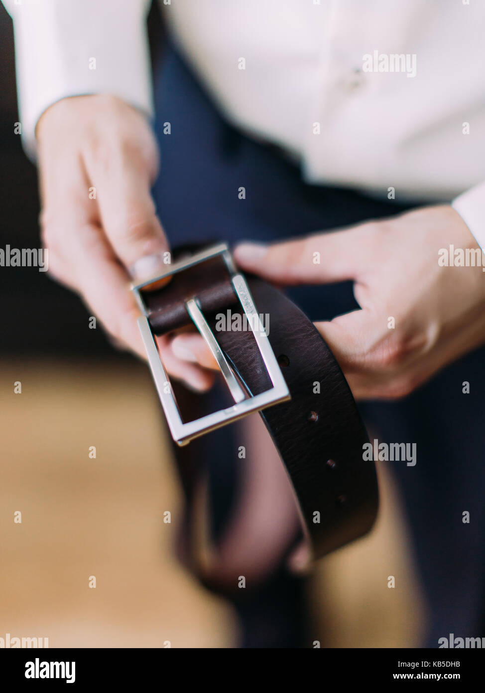 Hands of the groom holding the leather belt Stock Photo - Alamy
