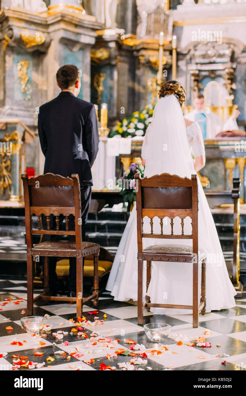 The vertical back view of the newlyweds during wedding ceremony in the ...