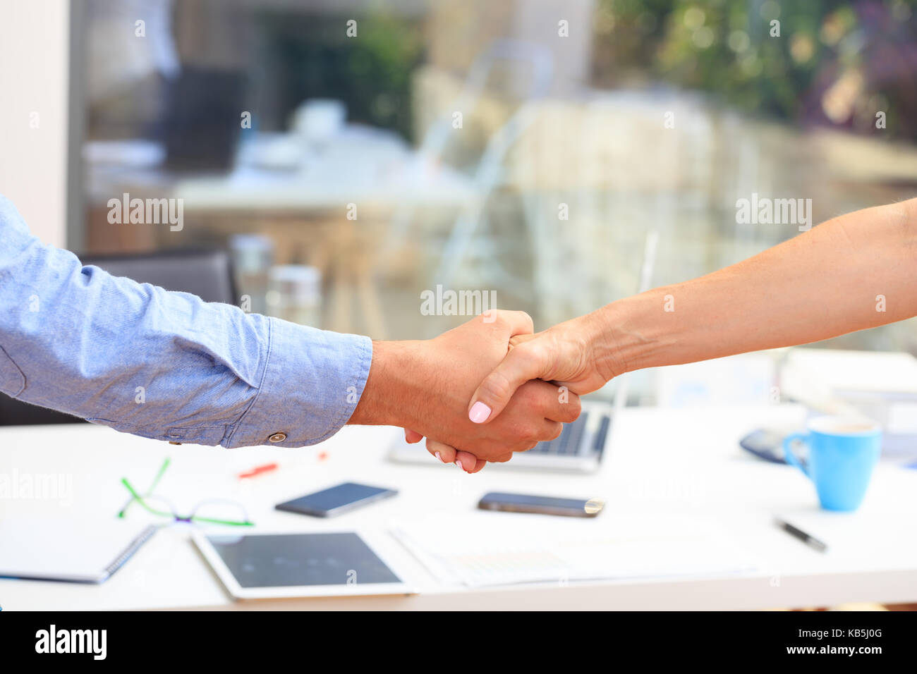 Business handshake in an office background Stock Photo - Alamy